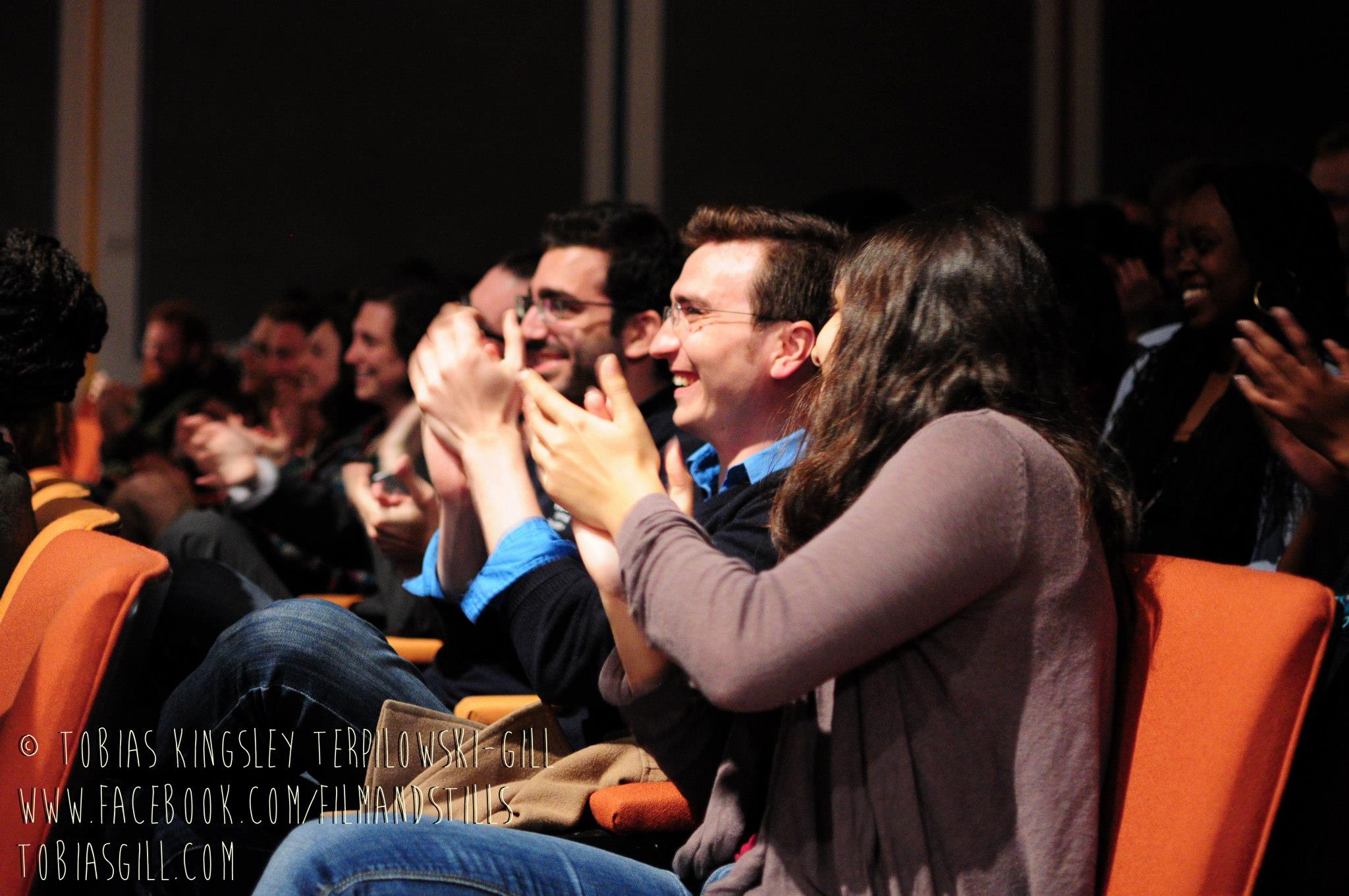 Friends in the audience smiling whilst watching a film